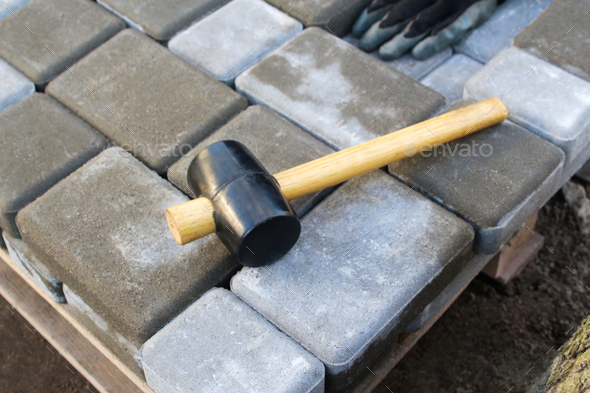 paving hammer. Stack of paving stones. Garden brick pathway paving by ...