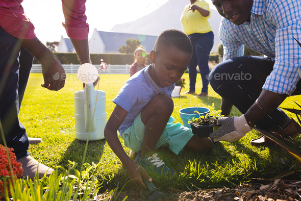 Multiracial boy with father and grandfather digging land and planting ...