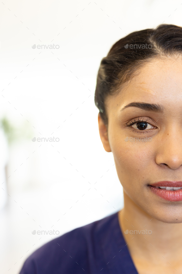 Vertical half face portrait of smiling biracial female healthcare ...