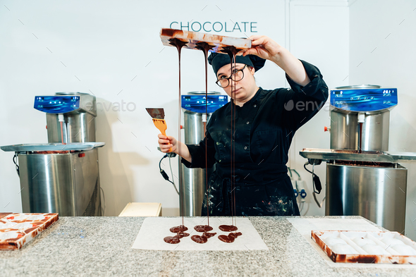 female chocolate master chef in black uniform working in confectionery ...