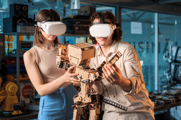 Young man and woman in VR glasses doing experiments in robotics in a ...