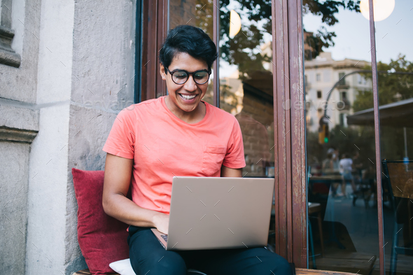Cheerful Latin guy 20s typing text message during netbook chatting Stock Photo by GaudiLab