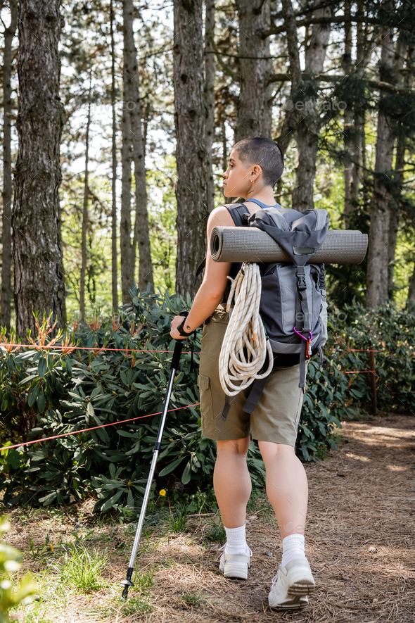 Side view of young short haired woman traveler with backpack holding ...