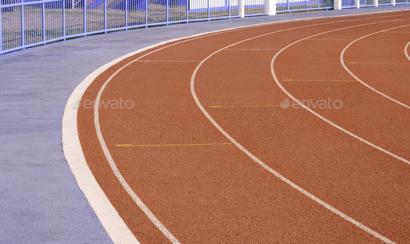 Empty red curve synthetic running tracks with pavement and fence in ...