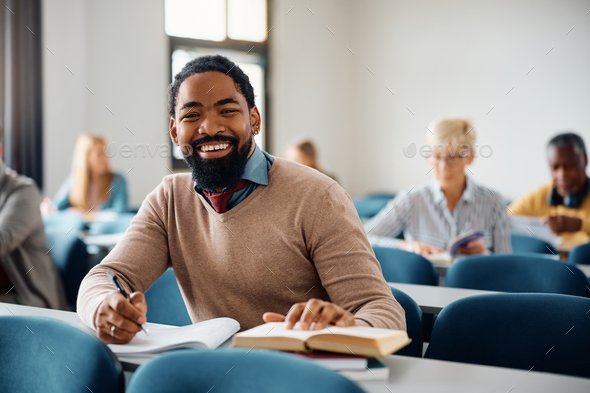 Happy black man taking notes while studying in the classroom and ...