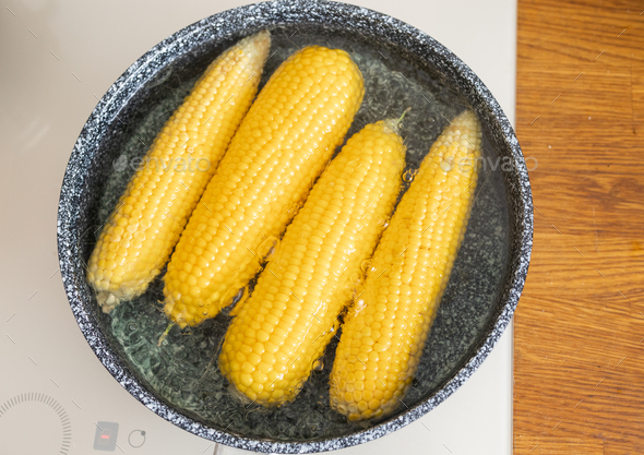 Boiled corn cobs in hot pan on the electric stove. Stock Photo by nikolast1
