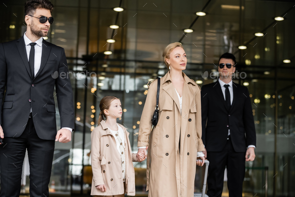 two bodyguards walking next to successful woman and preteen kid ...