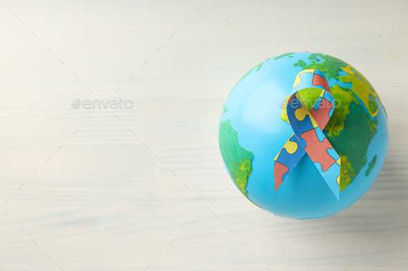 Ribbon with multi-colored puzzle pieces and a model of the planet Earth ...