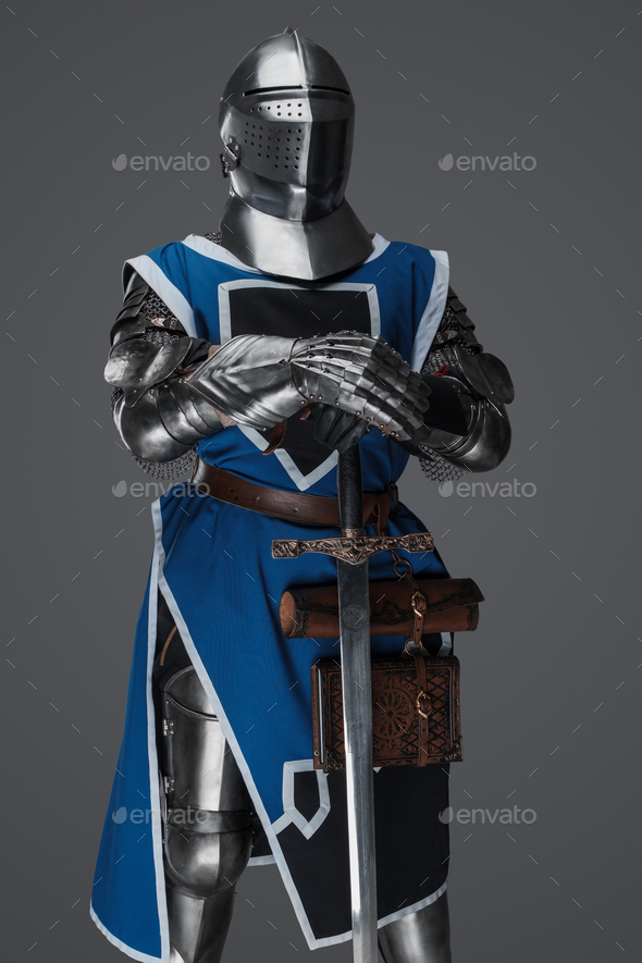 Medieval guard dressed in armor and blue surcoat holding a sword Stock ...