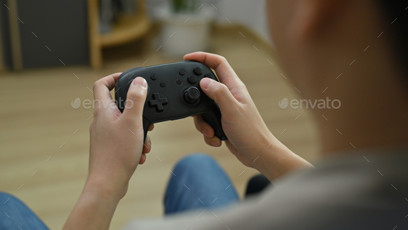 View over shoulder of young man holding wireless controller playing ...