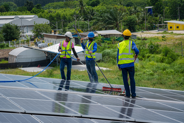 Professional worker cleaning solar panels with brush and water on roof ...