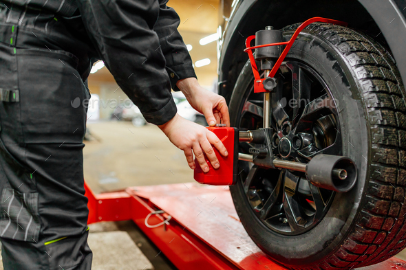 Car mechanic installing wheel alignment sensors Stock Photo by wirestock