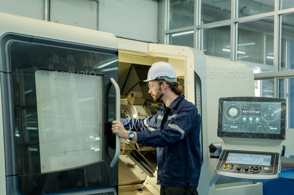 Engineer using laptop computer controlling automated robot hand with ...
