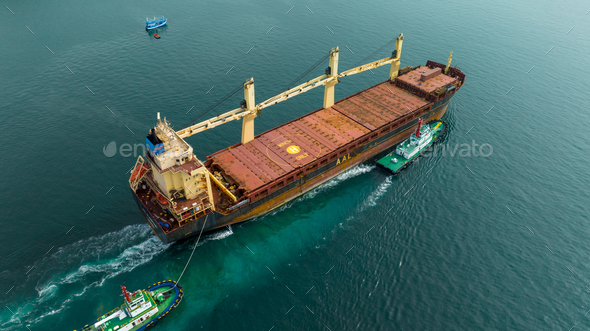 Aerial top view of cargo ship carrying container and running with tug ...