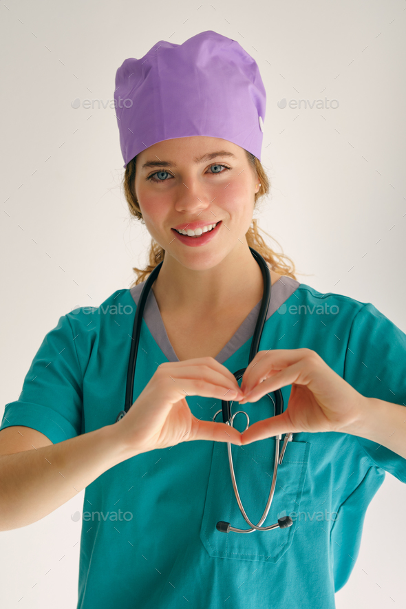 Cheerful medical worker making heart gesture on gray backdrop Stock ...