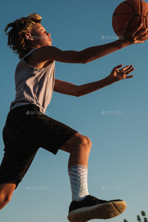 Active boy throwing basketball in hoop Stock Photo by ADDICTIVE_STOCK