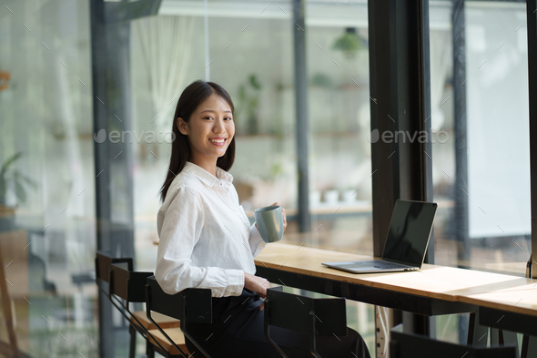 Young adorable Asian office worker working with laptop computer ...