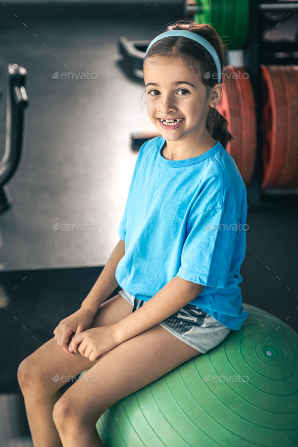Little girl doing exercises with big ball in gym. Stock Photo by puhimec