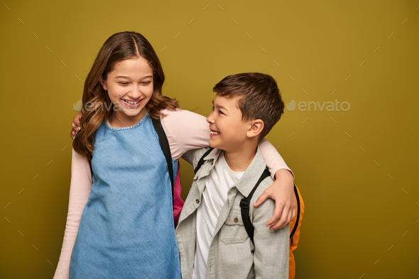Carefree preteen and multiethnic kids in casual clothes with backpacks ...