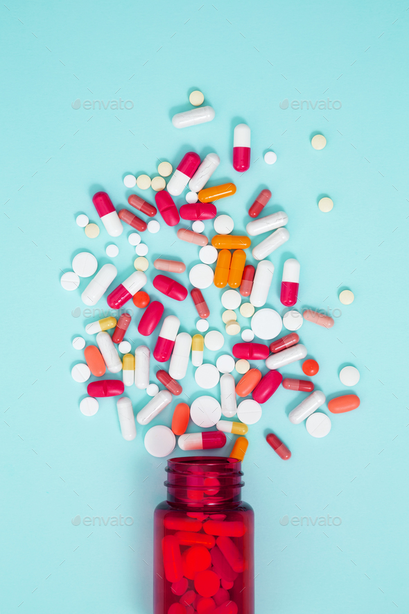 Orange bottle container with various colorful medication tablets and ...