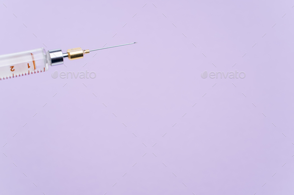 isolated sterilized glass injection syringe on a lilac paper background ...