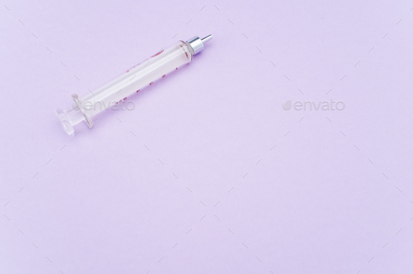 isolated sterilized glass injection syringe on a lilac paper background ...