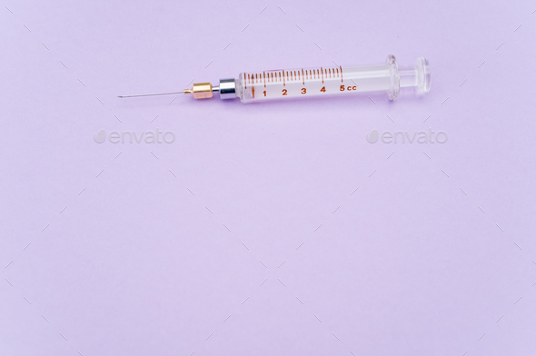 isolated sterilized glass injection syringe on a lilac paper background ...