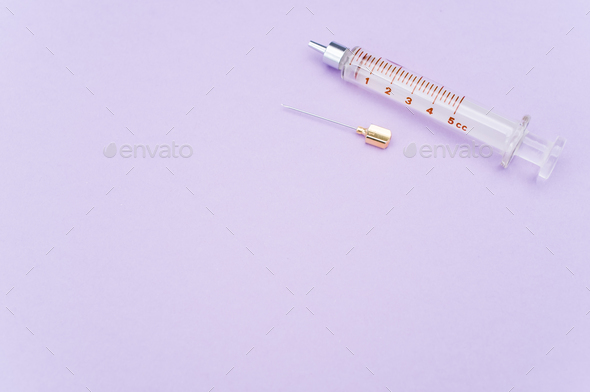 isolated sterilized glass injection syringe on a lilac paper background ...