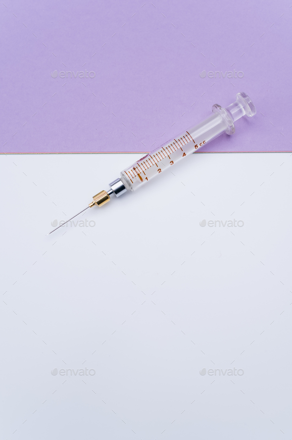 isolated sterilized glass injection syringe on a lilac paper background ...