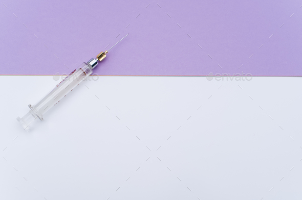 isolated sterilized glass injection syringe on a lilac paper background ...