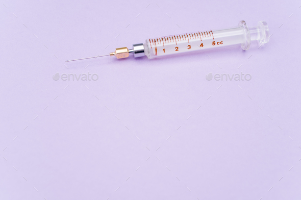 isolated sterilized glass injection syringe on a lilac paper background ...
