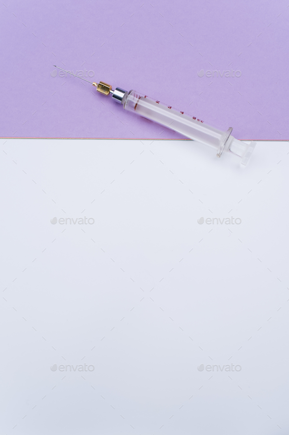 isolated sterilized glass injection syringe on a lilac paper background ...