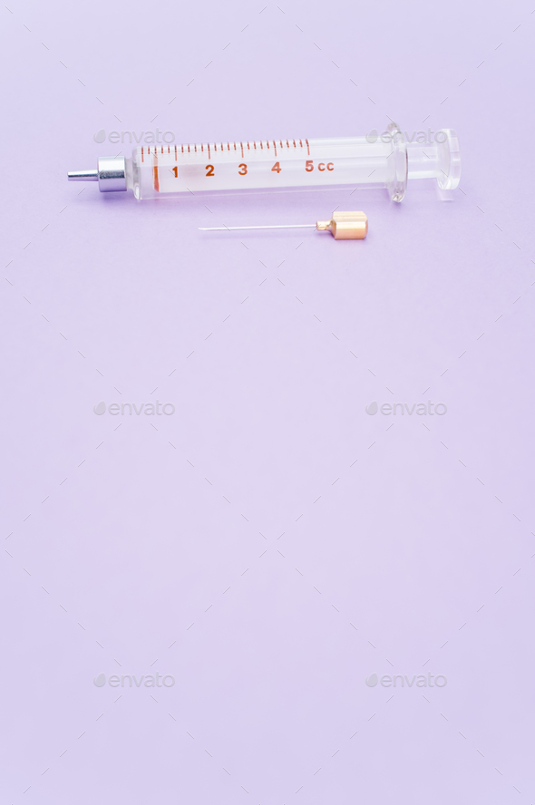 isolated sterilized glass injection syringe on a lilac paper background ...