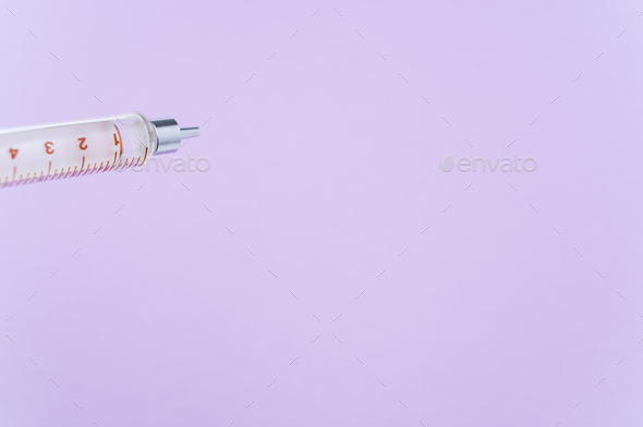 isolated sterilized glass injection syringe on a lilac paper background ...
