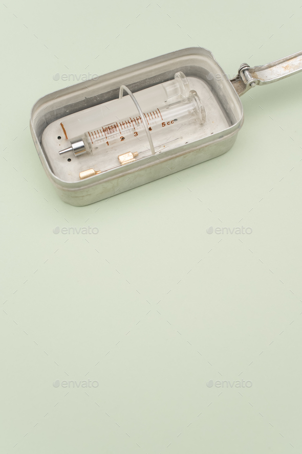 isolated sterilized glass injection syringe in a box on a green ...