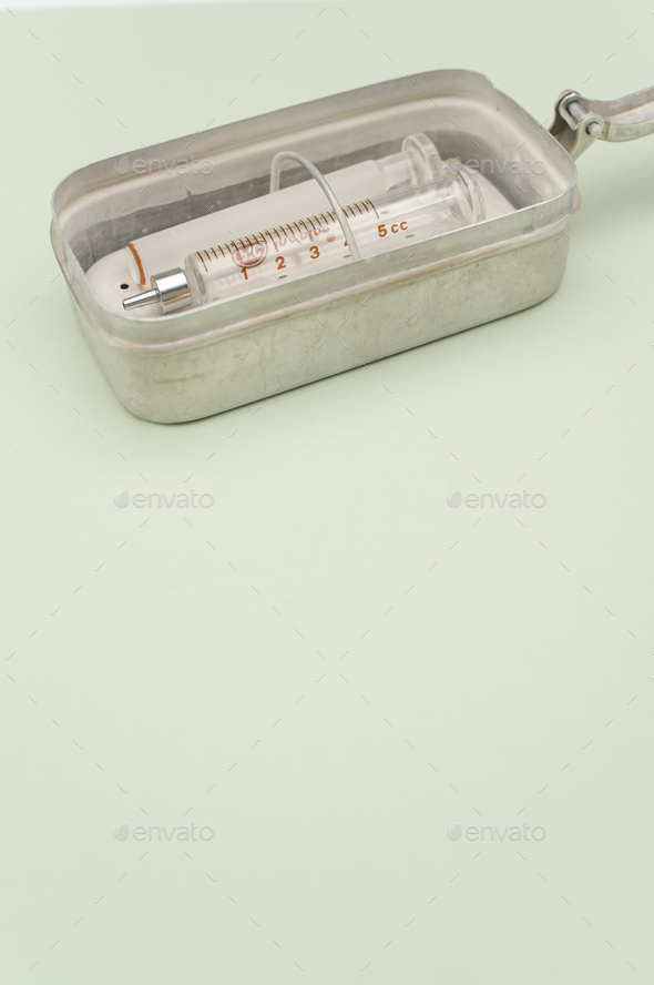 isolated sterilized glass injection syringe in a box on a green ...