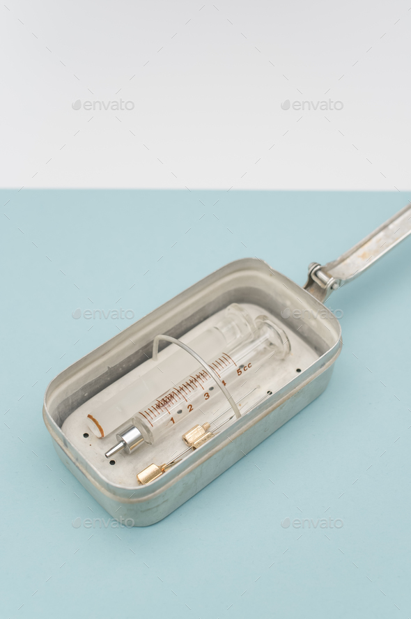 isolated sterilized glass injection syringe in a box on a blue ...