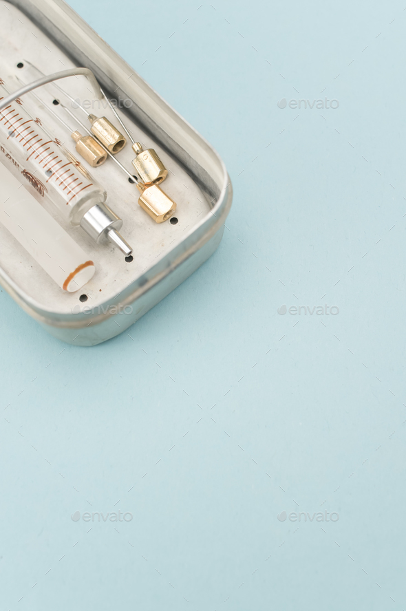 isolated sterilized glass injection syringe in a box on a blue ...