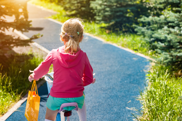 Rear view of little kid riding bike in summer urban park, outdoors ...