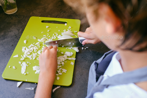 Crop boy chopping fresh onion while cooking in kitchen Stock Photo by ...