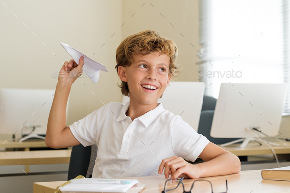 Delighted schoolboy playing with paper airplane in classroom Stock ...