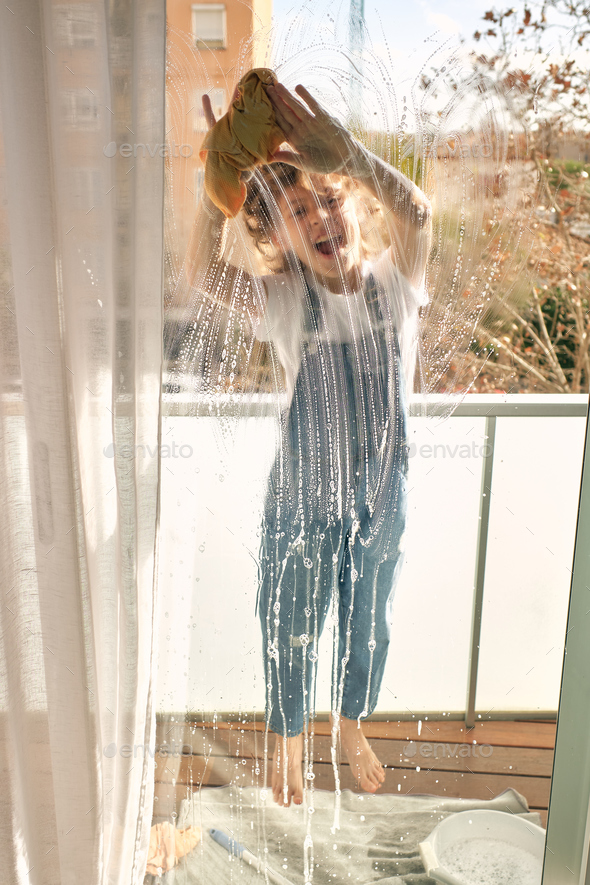 Cheerful boy washing windows with rag at home Stock Photo by ADDICTIVE ...
