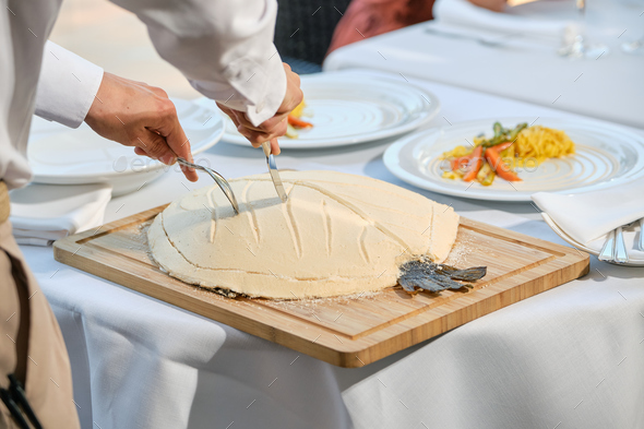 Crop waiter serving fish baked in salt crust Stock Photo by ADDICTIVE_STOCK