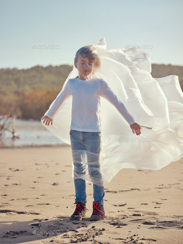 Boy with plastic bag around body on beach Stock Photo by ADDICTIVE_STOCK