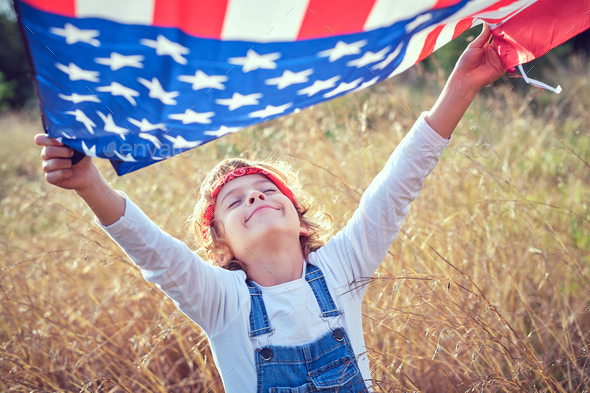 Preteen boy waving American flag in field Stock Photo by ADDICTIVE_STOCK