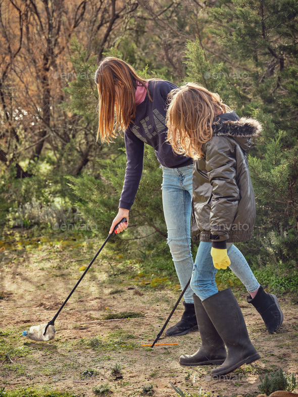 Teen girls picking up garbage with trash grabber in park Stock Photo by ...