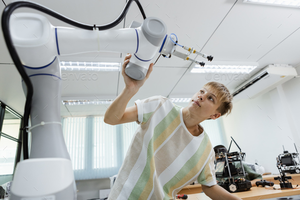 Boy caucasian education electronic robotic arm on table at class room ...