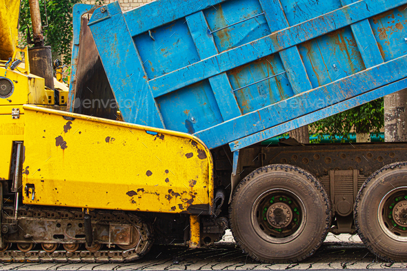 Loading fresh asphalt into the paver, unloading asphalt from the truck ...