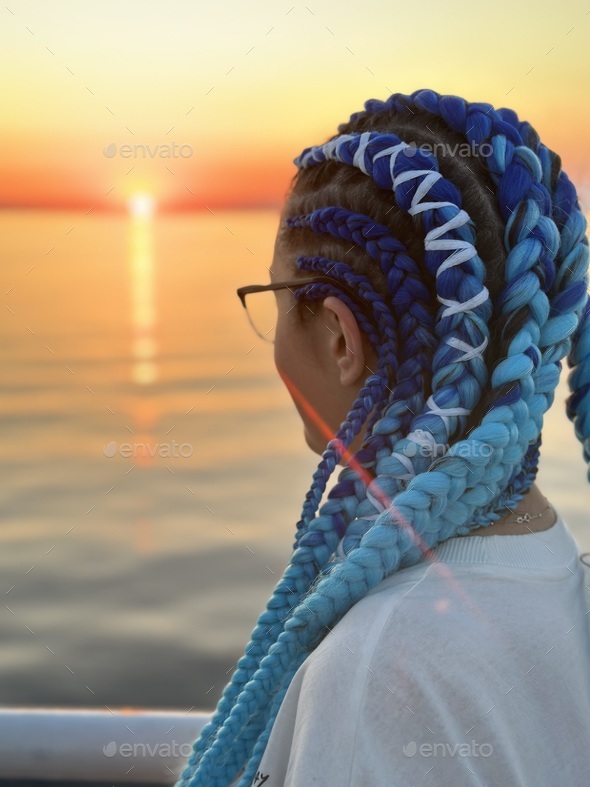 A girl with blue braids on the sunset background Stock Photo by ellirocker