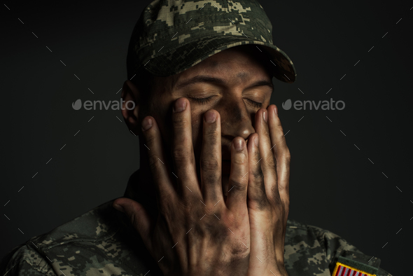 military man with closed eyes covering face with dirty hands and ...